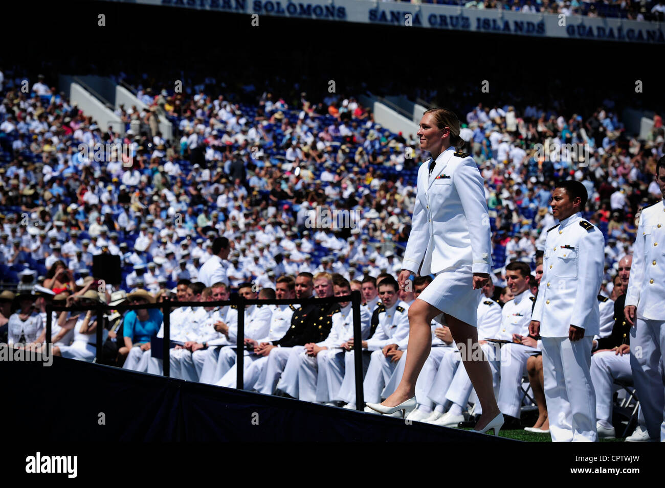 A newly commissioned ensign walks across the stage to receive her ...