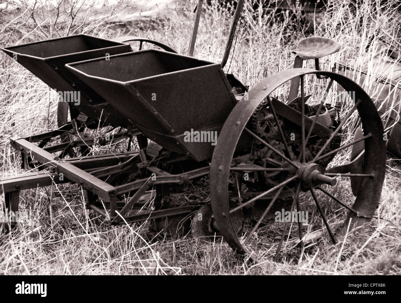 A retired rustic seeder sits ready-to-go on a old abandoned farm in ...