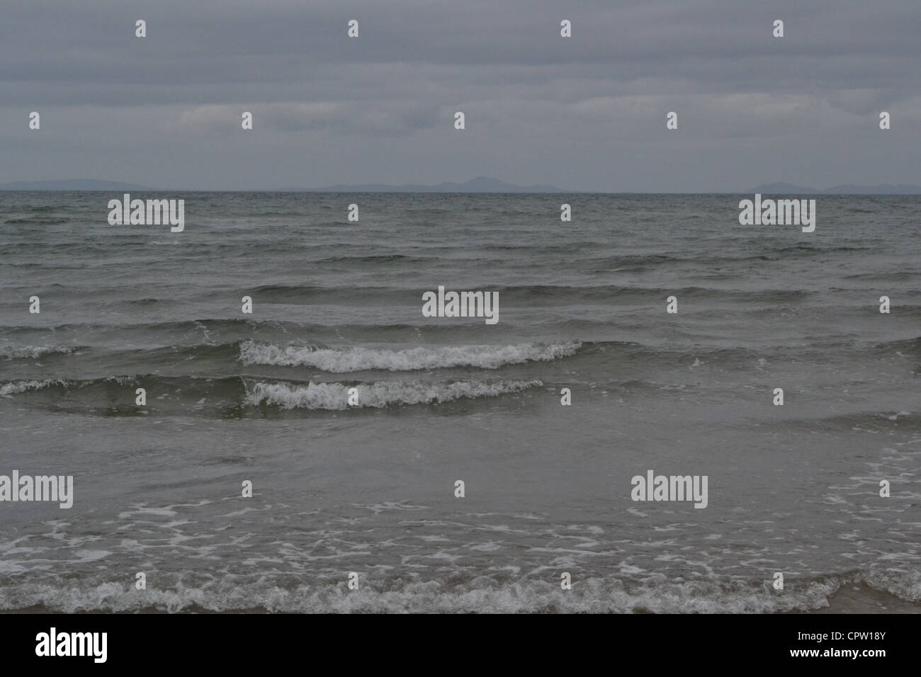 Dull day on the beach. Small waves crashing Stock Photo - Alamy