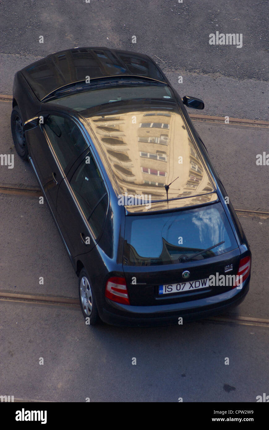 Urban street scene. Car with reflection of apartment block in car roof ...