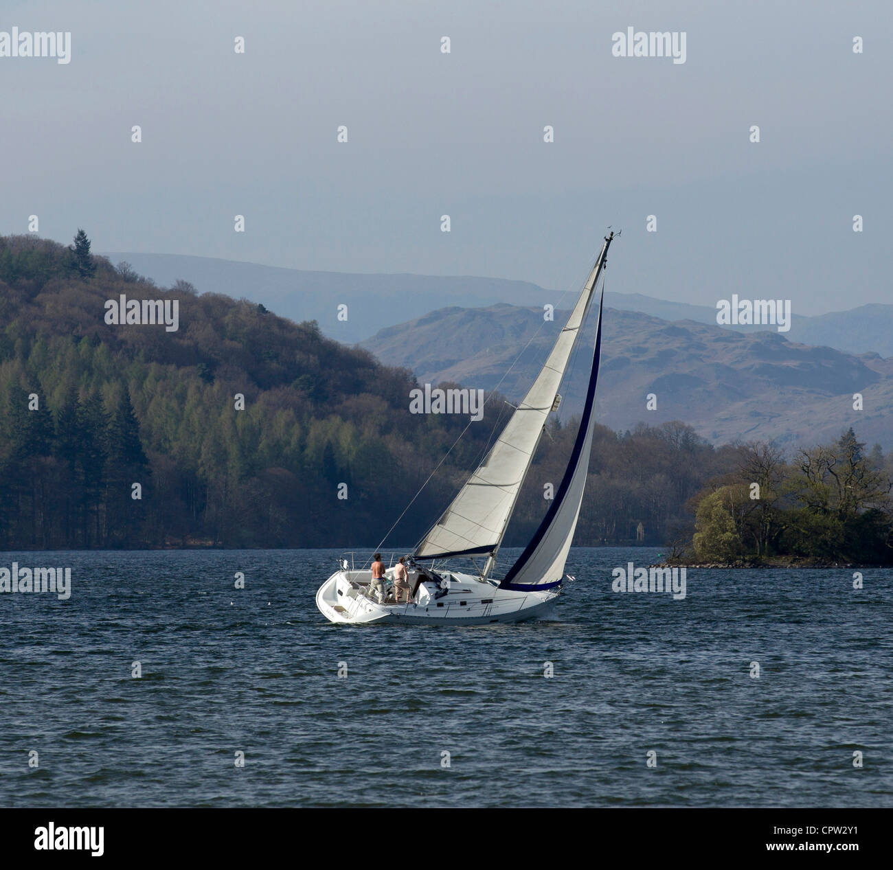 yacht under full sail in winter on Lake Windermere with the mountains ...
