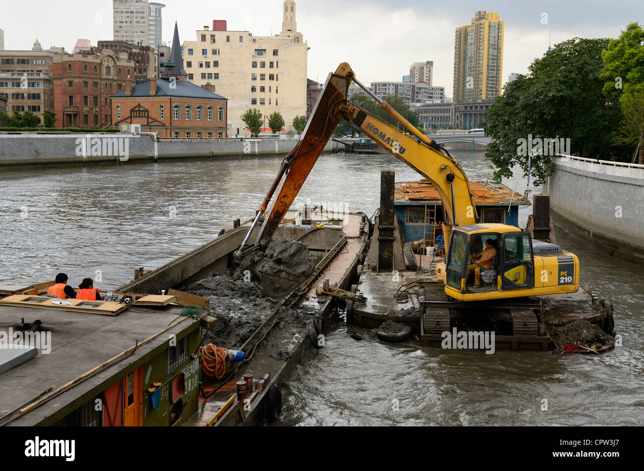 Excavator and barge dredging sludge out of the Wusong river at the ...