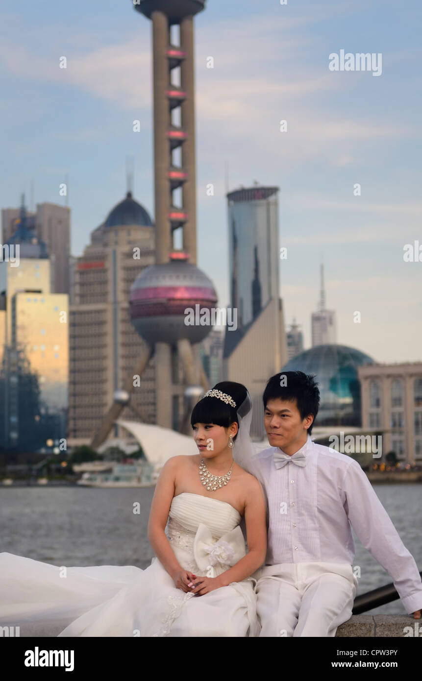 Wedding couple in white on the Bund with Pudong high rise towers ...