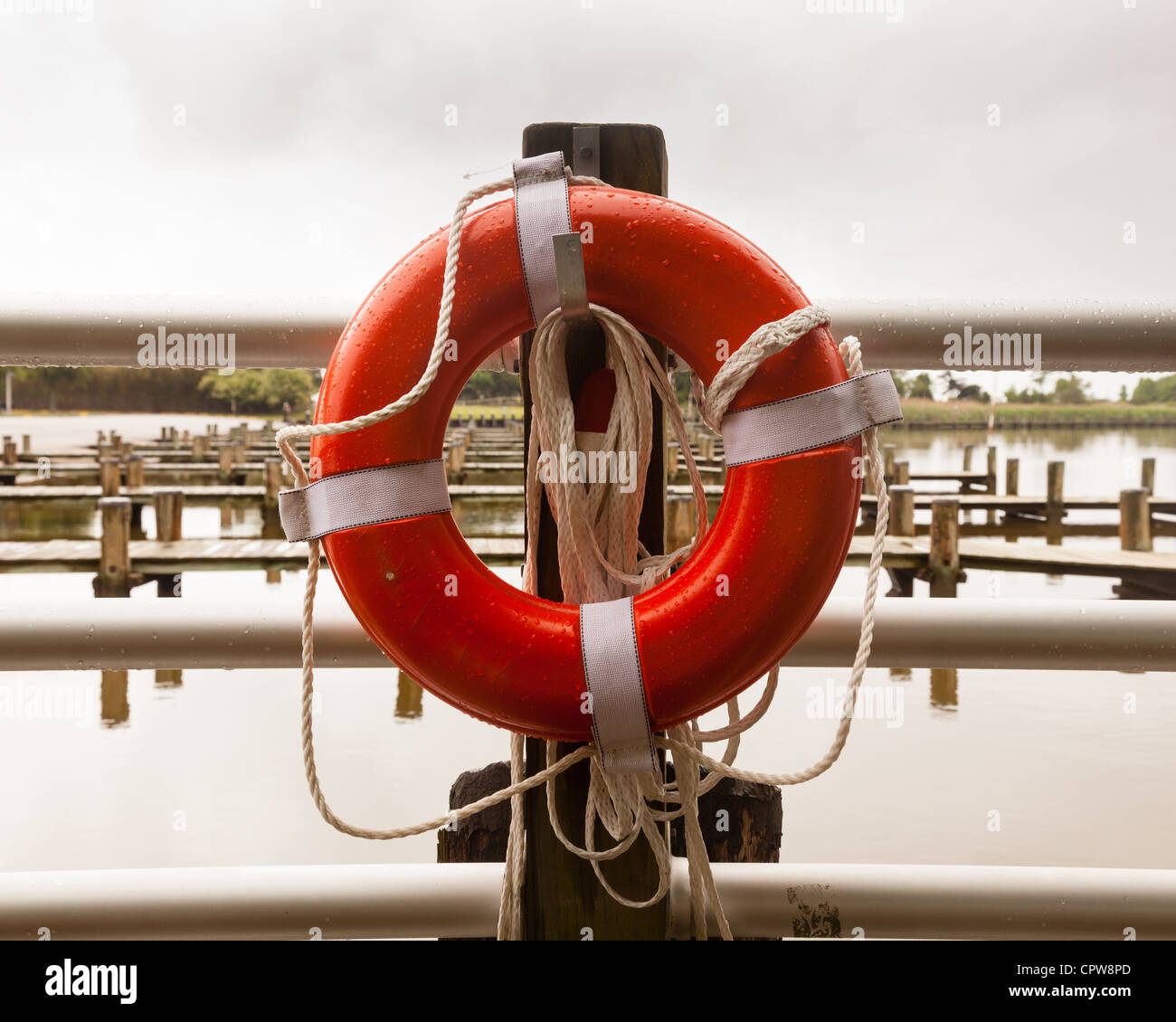 Lone red life ring and rope in front of empty boat docks on a cloudy ...