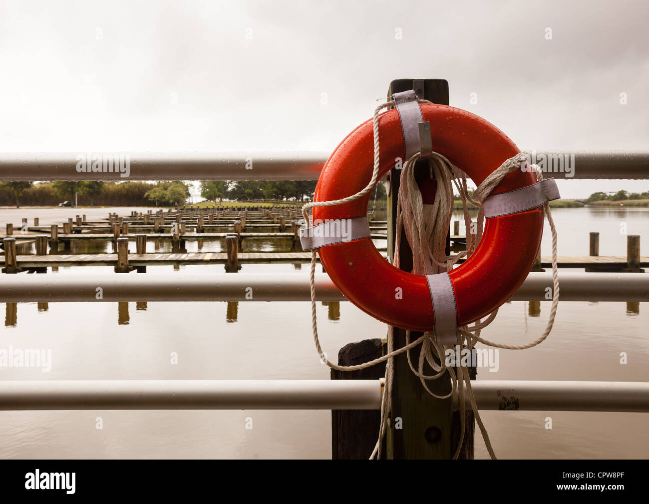 Lone red life ring and rope in front of empty boat docks on a cloudy ...