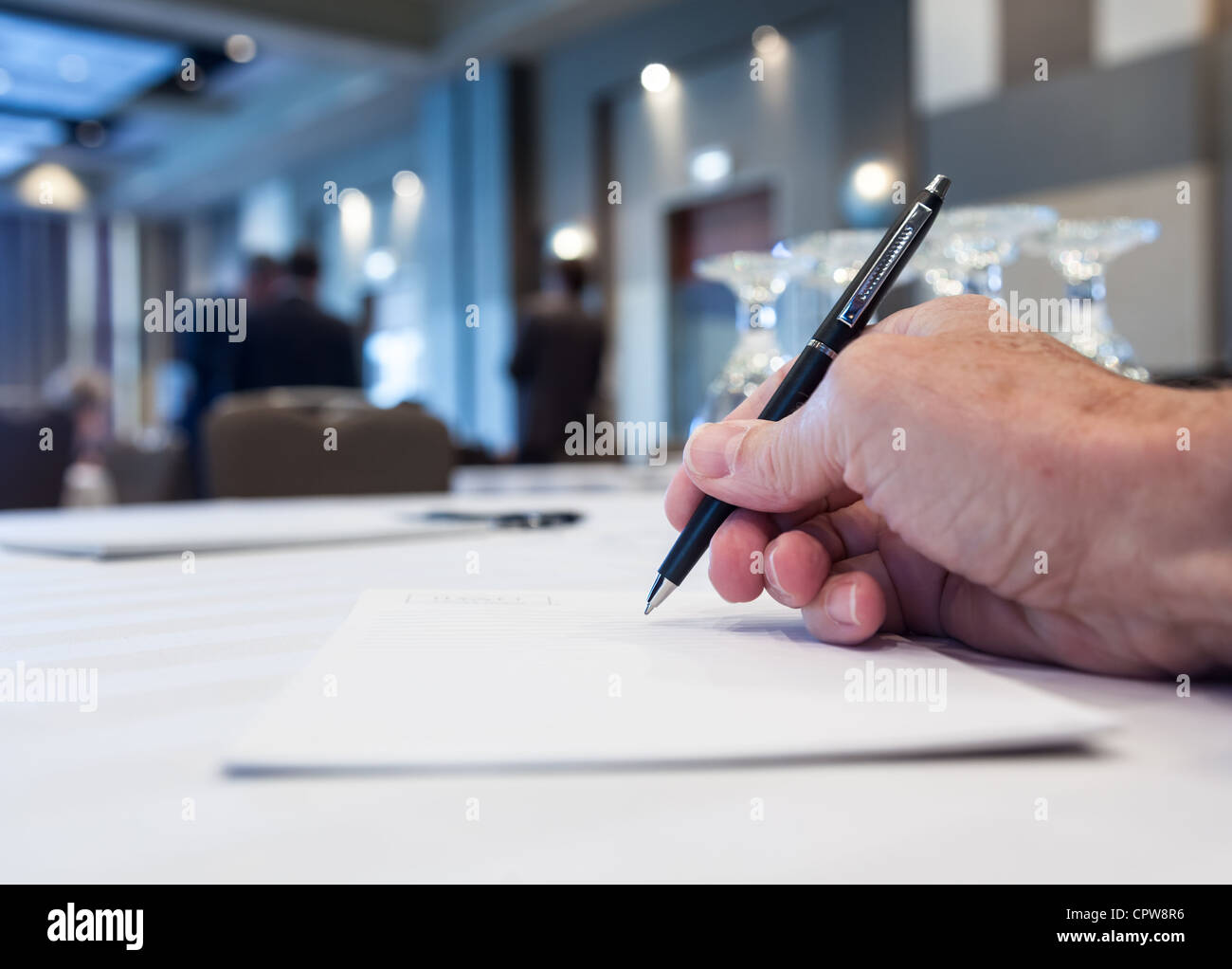 Conference table with hand taking notes or minutes with people in ...