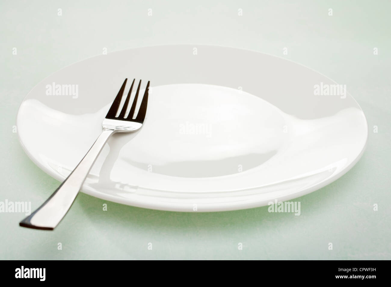 White plate and modern fork on simple plain green background Stock ...