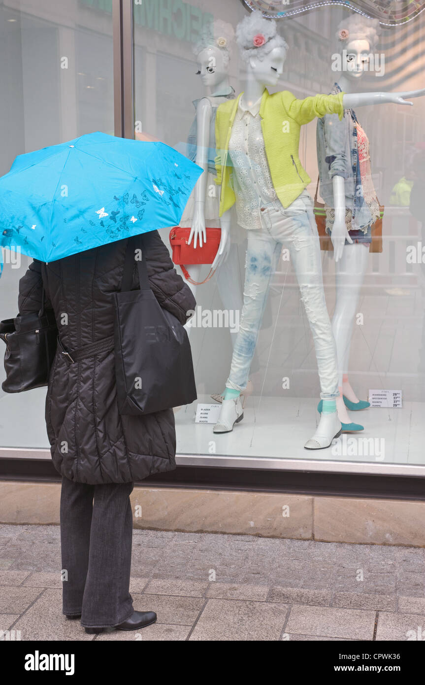 Woman standing in the rain while looking at summers clothes in a shop ...