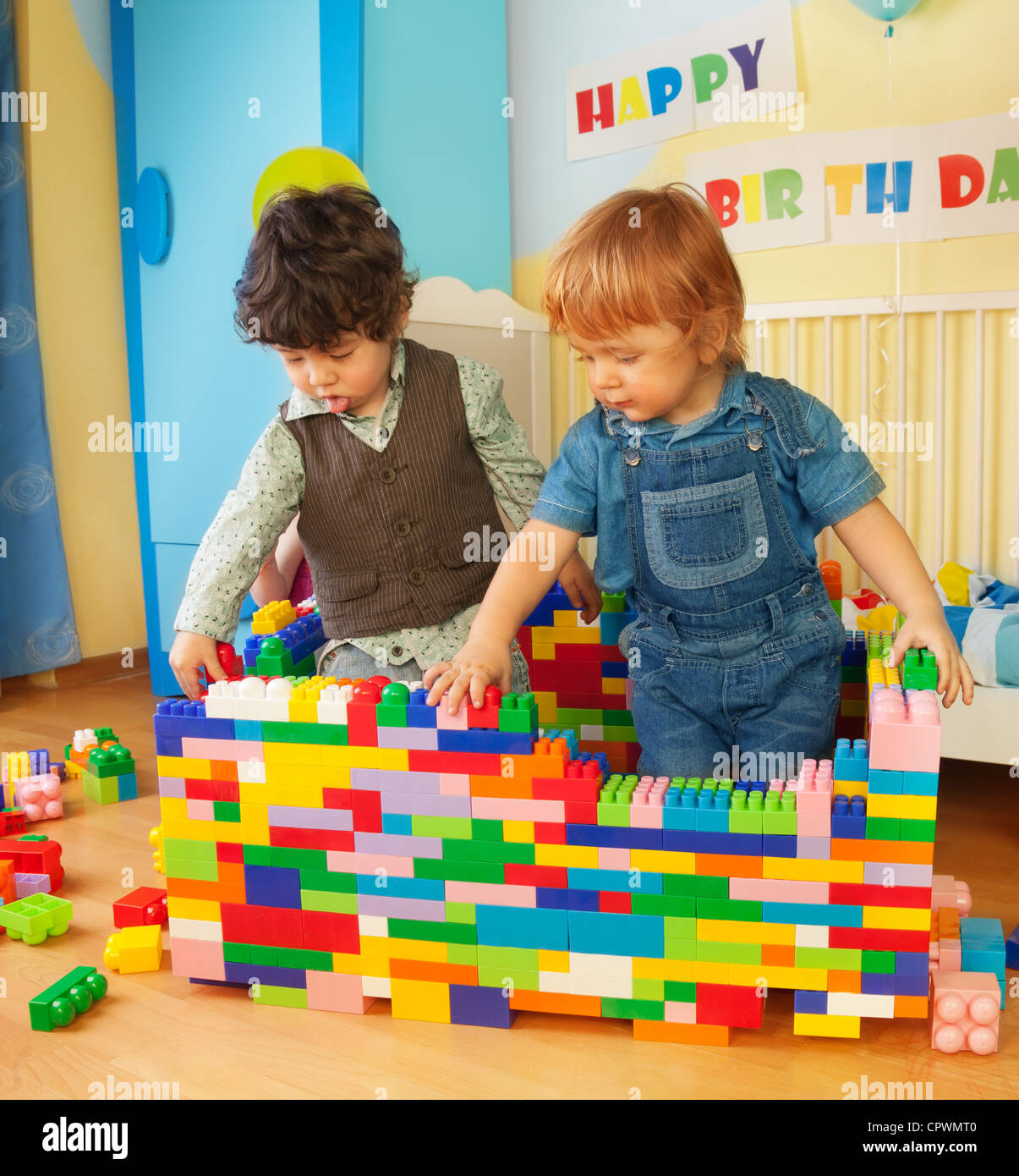 Kids building a wall of plastic blocks sitting in bedroom Stock Photo ...