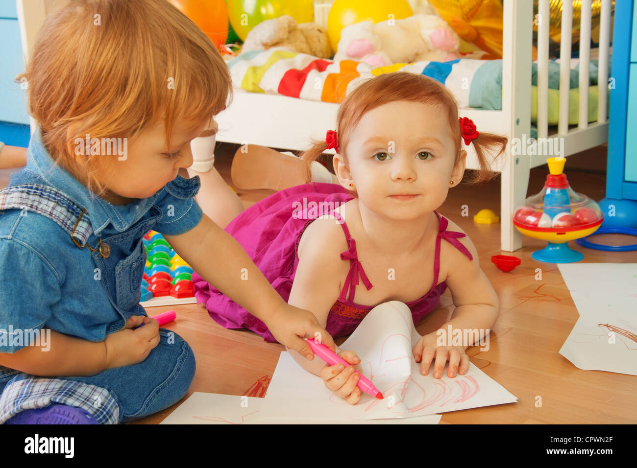 Boy and girl drawing with crayons sitting and laying on the floor Stock ...