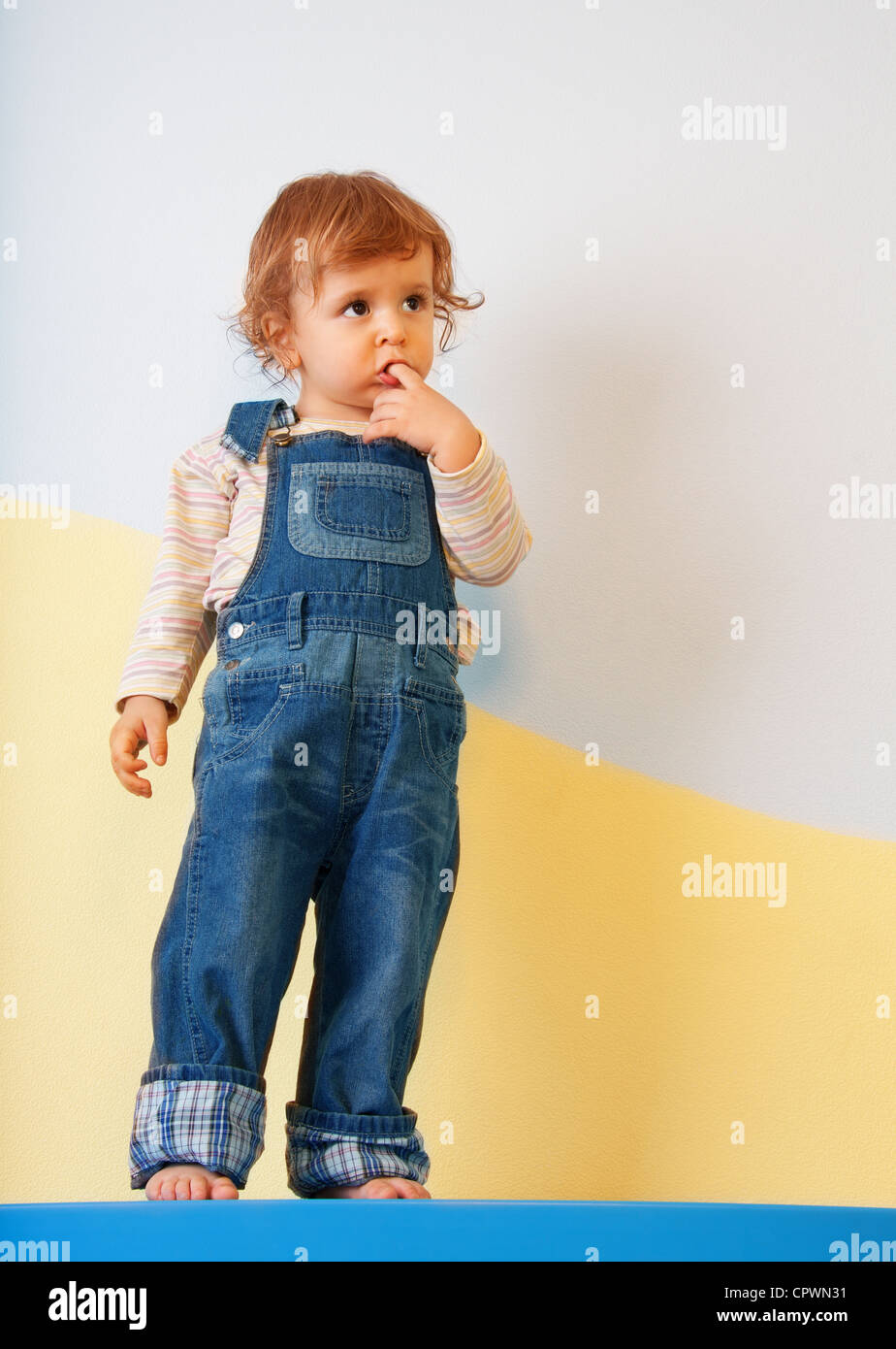 Thoughtful kid standing on the furniture Stock Photo - Alamy