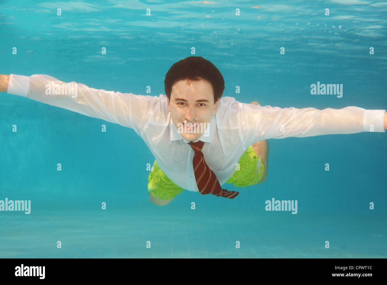 Business man swimming underwater in the pool wearing white shirt and ...
