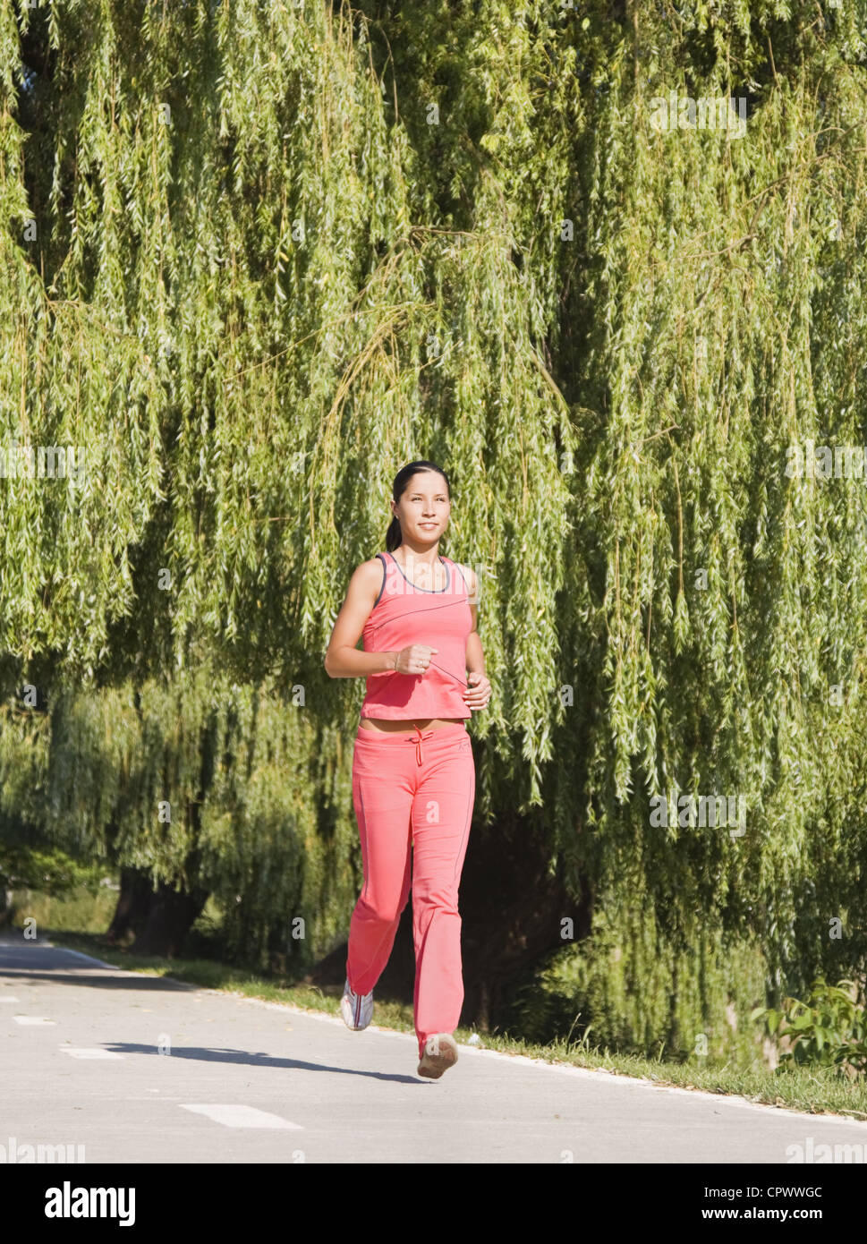 Young woman running in a park near a drooping willow tree Stock Photo ...