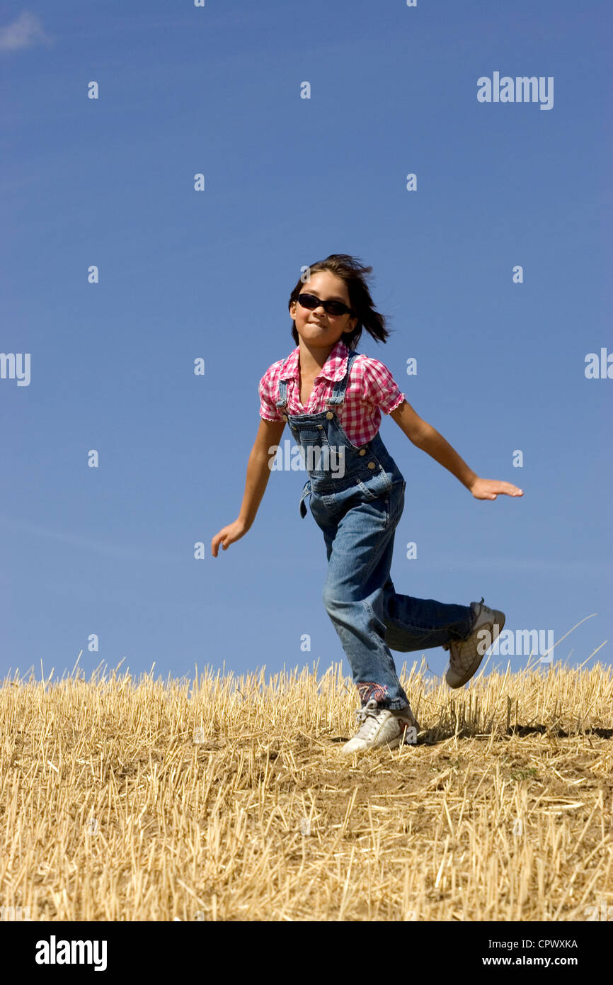 A girl skips along happily in a harvested wheat field Stock Photo - Alamy