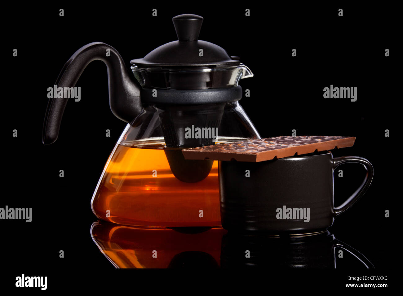 Tea in transparent glass pot with chocolate laying on the dark mug ...