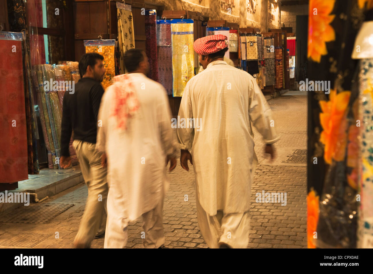 Arab men walk on the street lined with shops, Dubai, United Arab ...