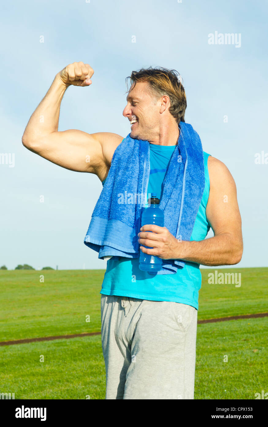 A man playfully flexes his arm muscles while holding a water bottle ...