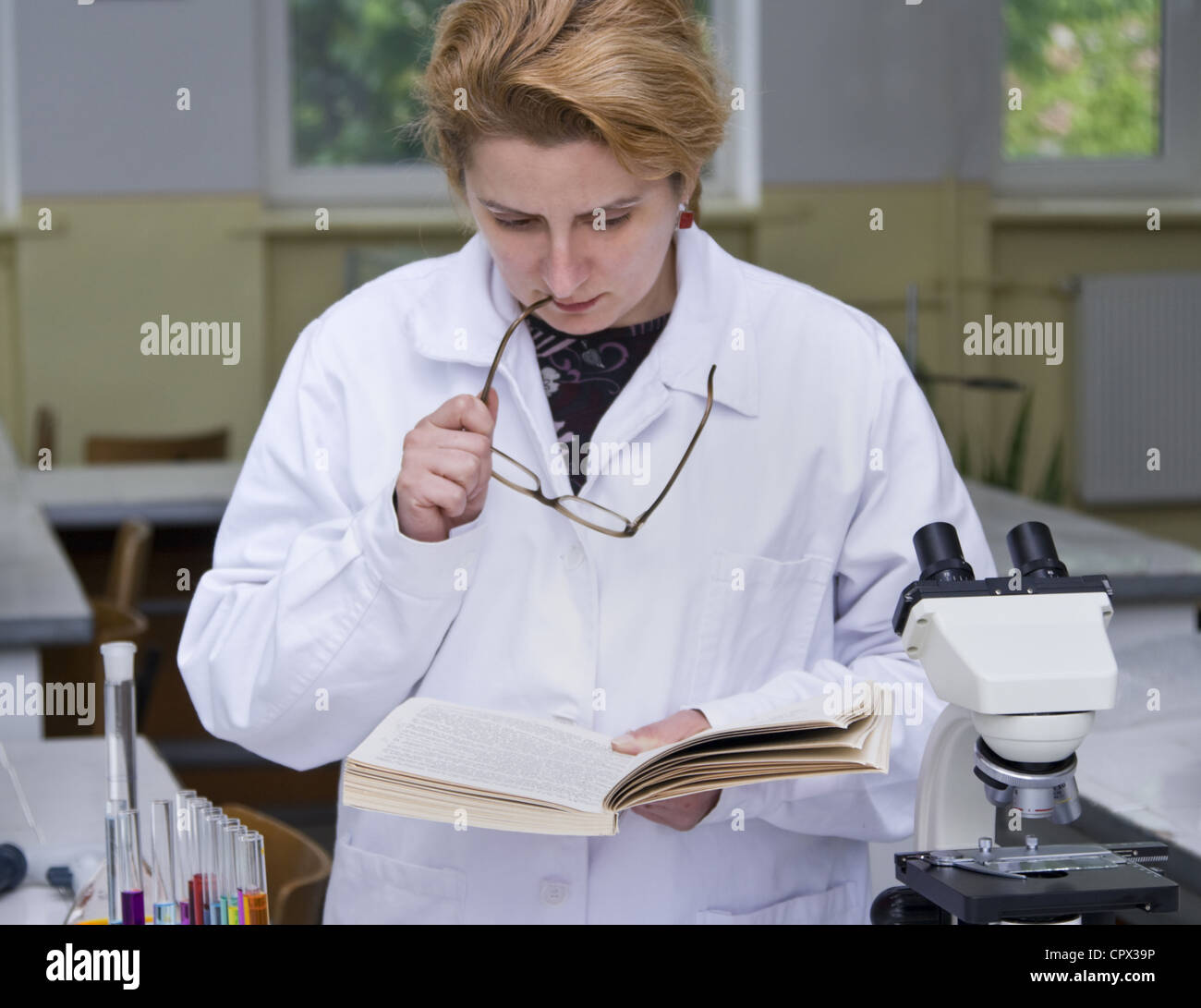 Female researcher reading something in a textbook during her experiment ...