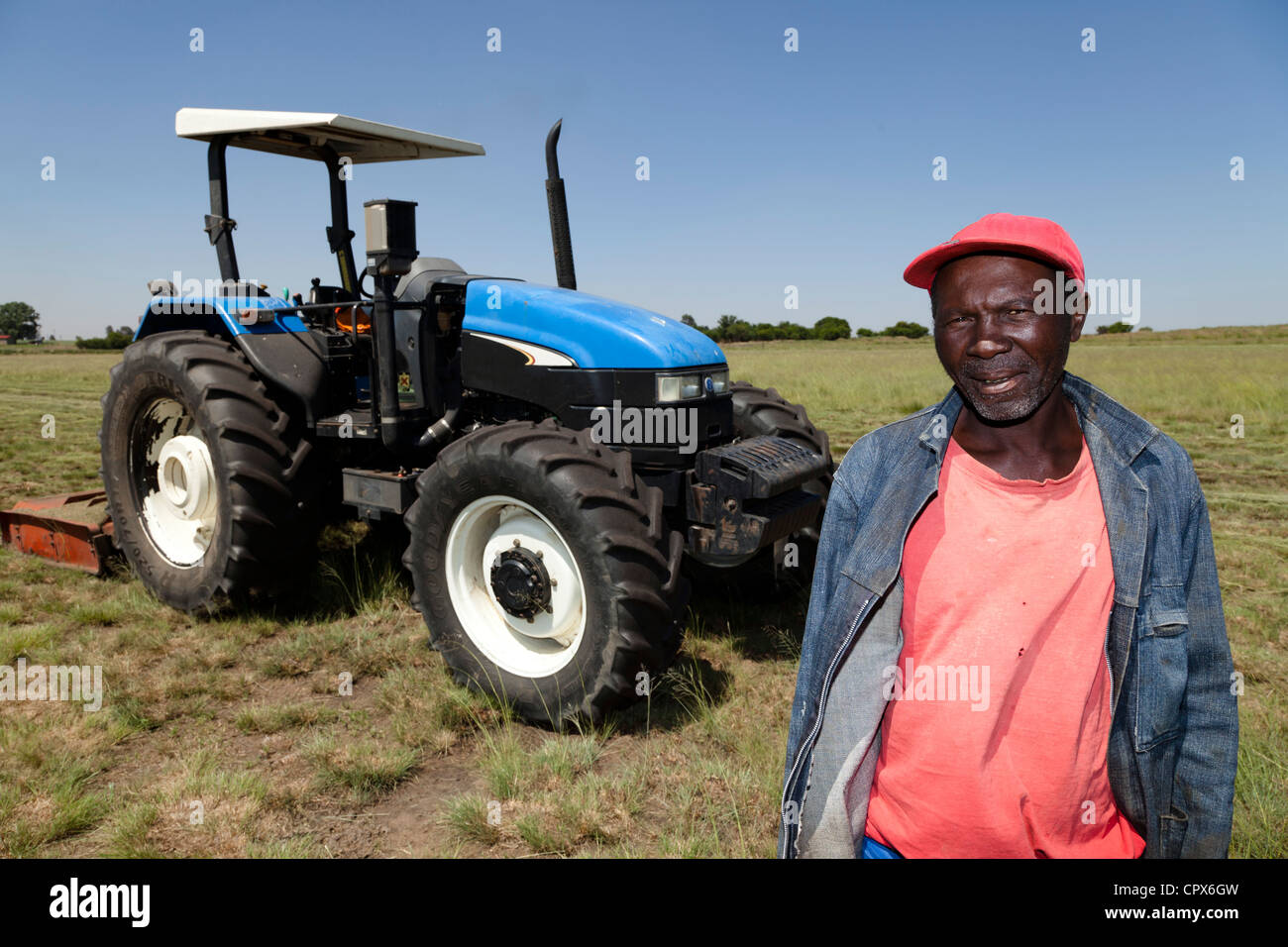 African farmworker standing in a field in front of tractor Stock Photo ...