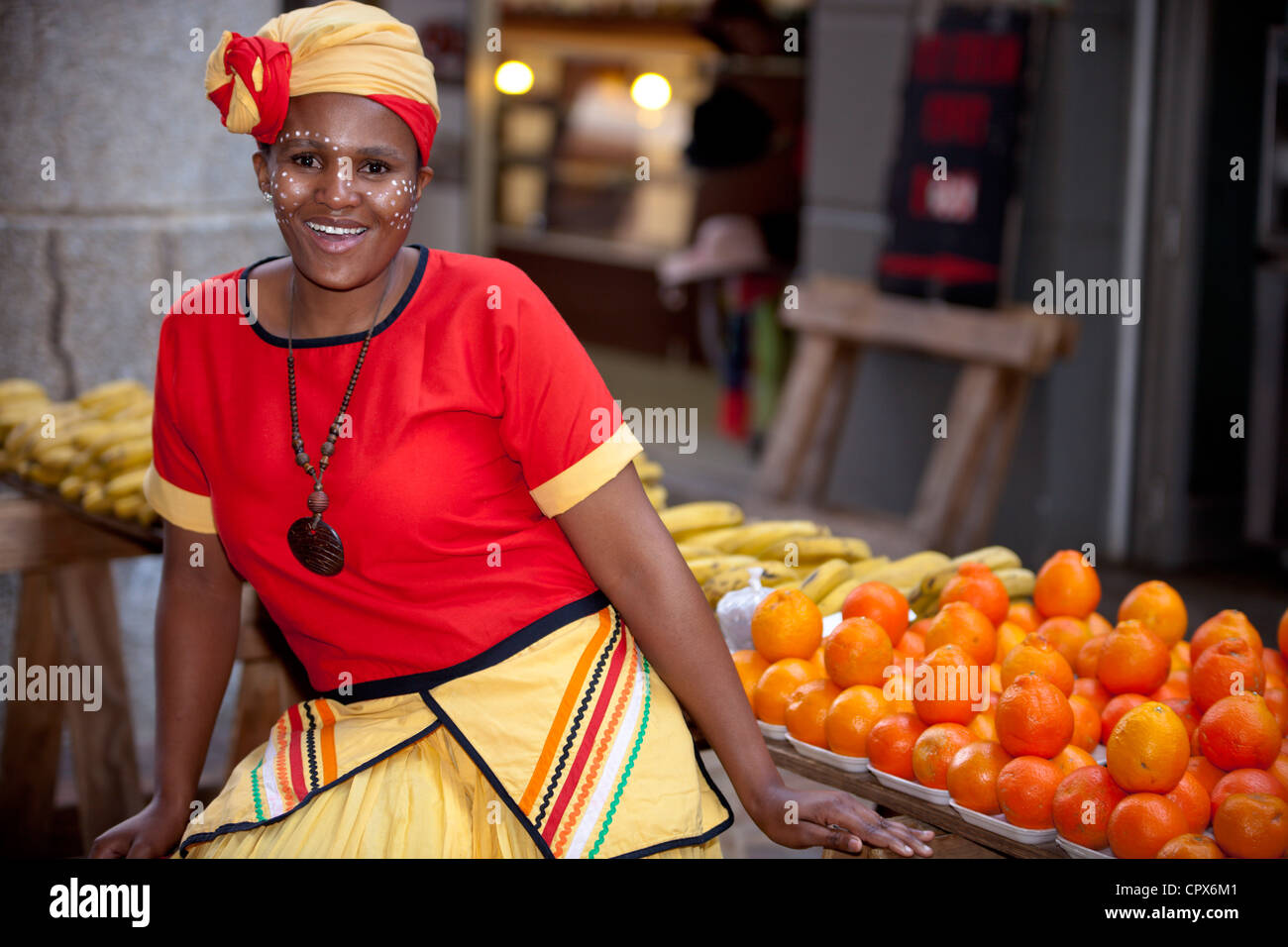 Street vendor dressed in traditional clothing smiles at the camera ...