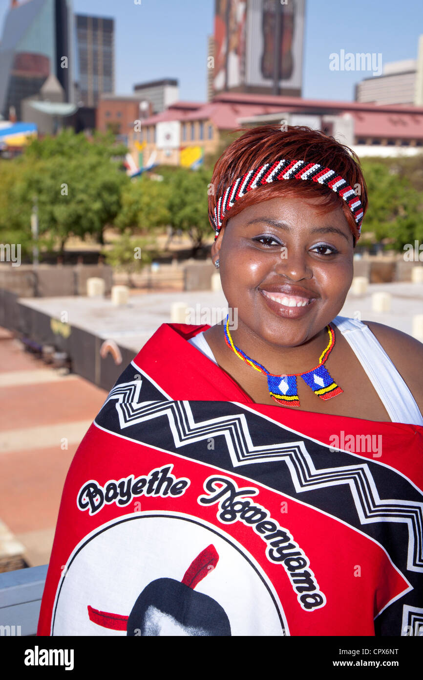 African woman dressed in traditional clothing smiles at the camera ...