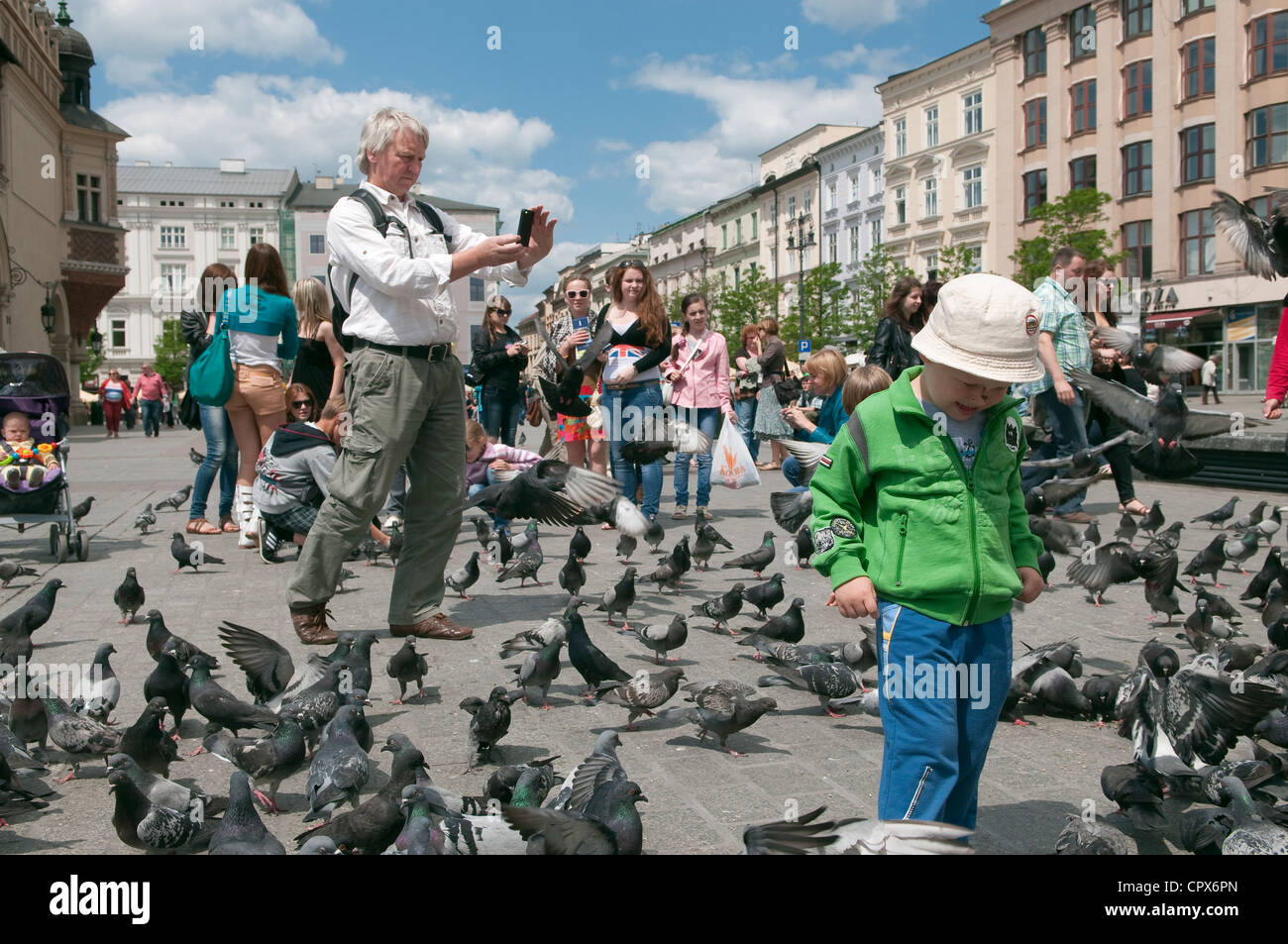 Crying child among pigeons in crowded Main Market Square, Krakow ...