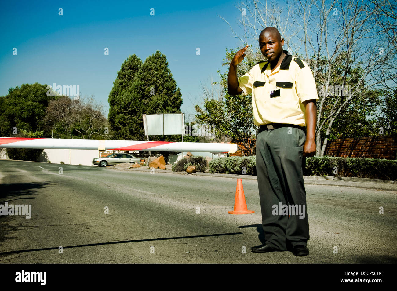 A security guard raising a salute while guarding a boom gate Stock ...