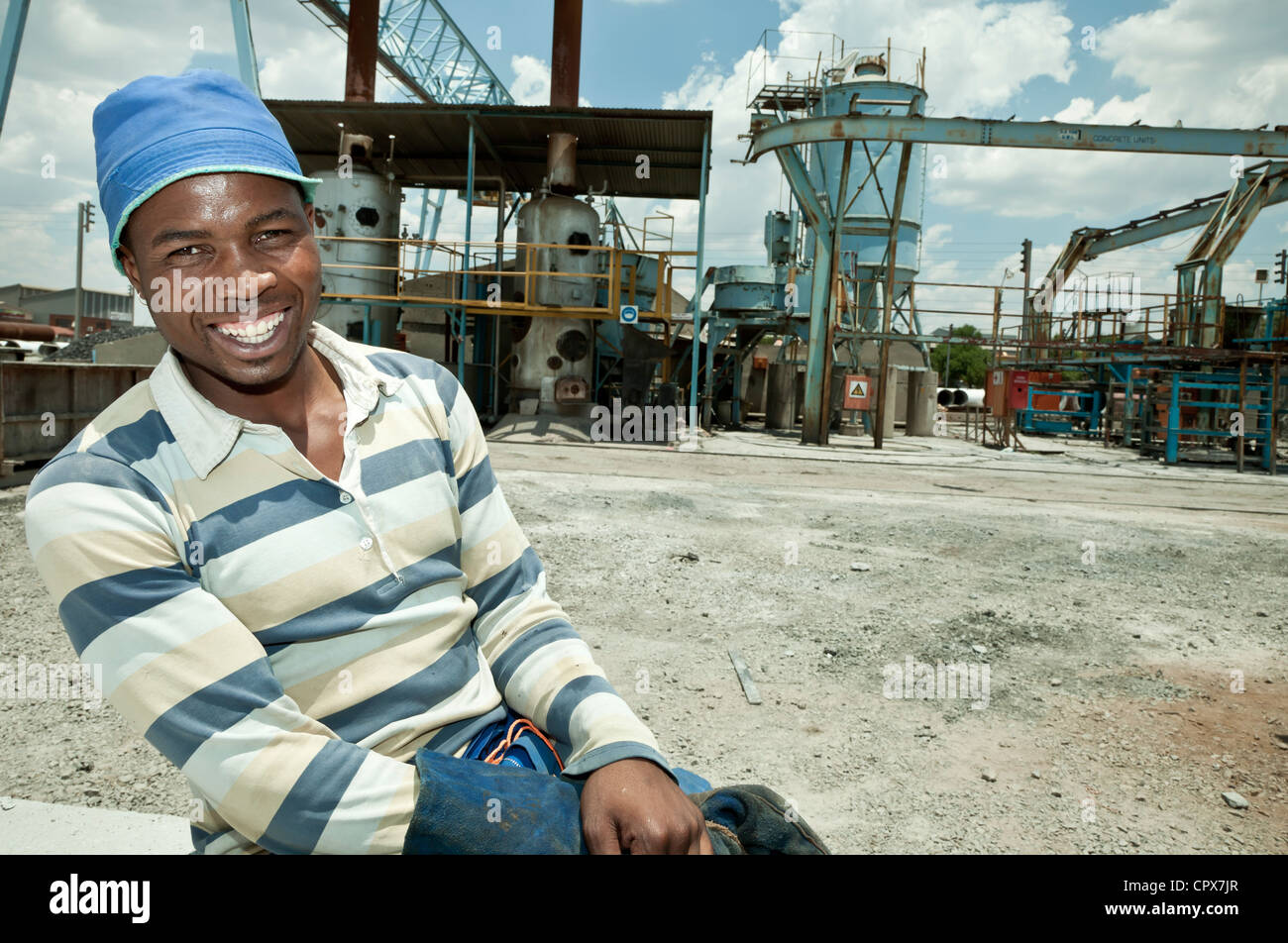 Black factory worker sits in construction yard smiling at camera Stock ...