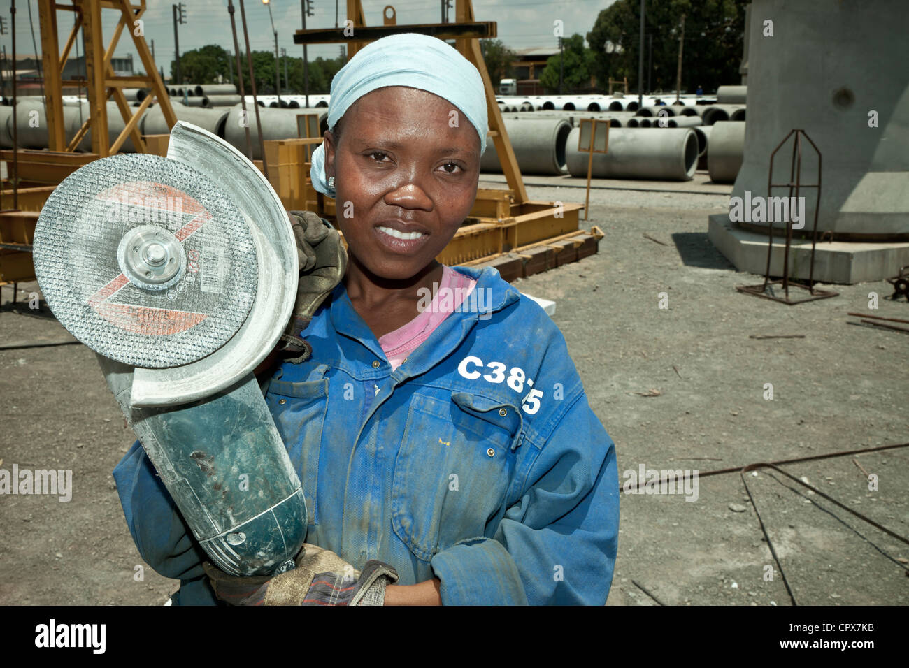Black female factory worker holding angle grinder smiles at camera ...