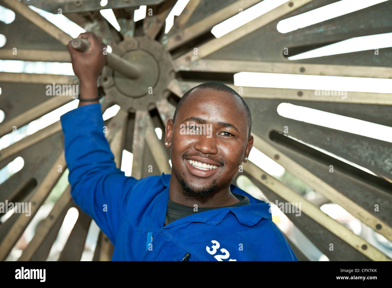 Black factory worker works on a machine while smiling at camera Stock ...