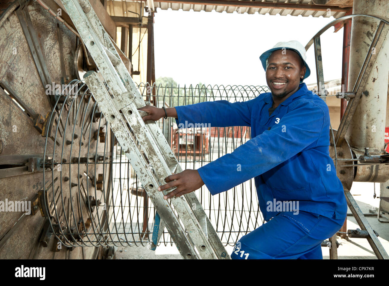 Black factory worker climbs ladder while smiling at camera Stock Photo ...