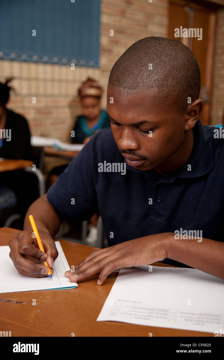 Male student working at a desk Stock Photo - Alamy