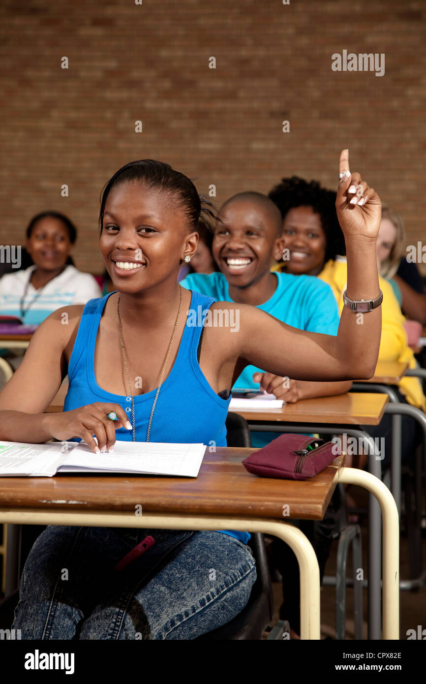 Female student at a desk raising her hand Stock Photo - Alamy