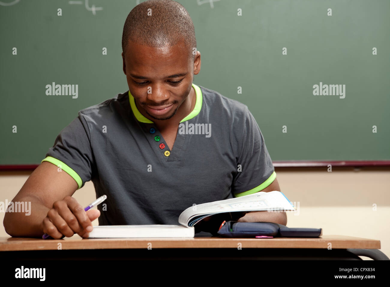Male student studying at a desk Stock Photo - Alamy