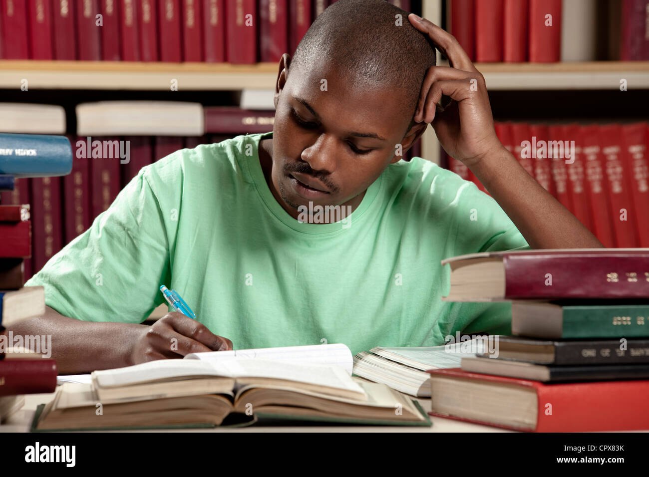 Male student studying with lots of books Stock Photo - Alamy