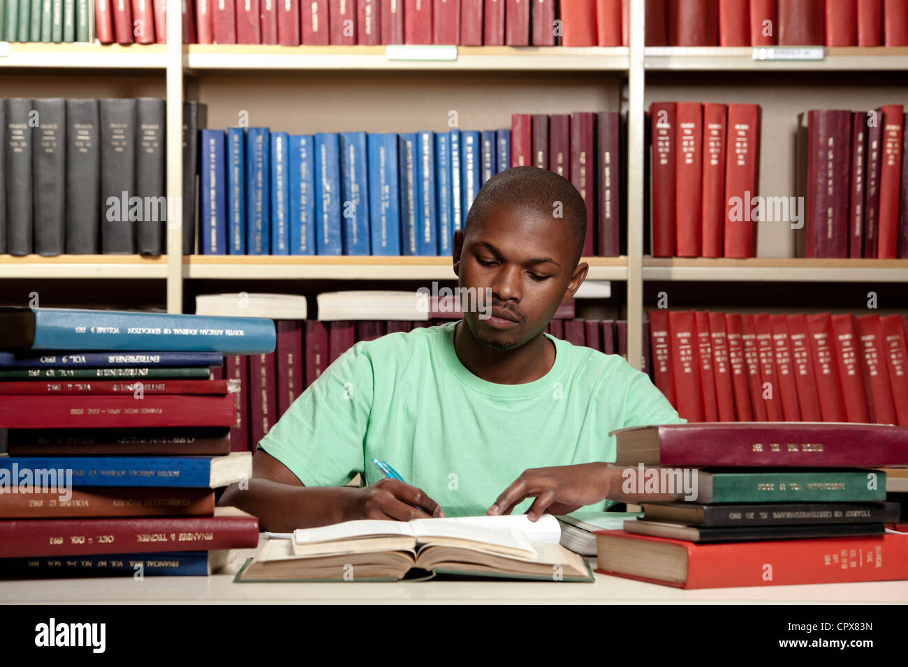 Male student studying with lots of books Stock Photo - Alamy