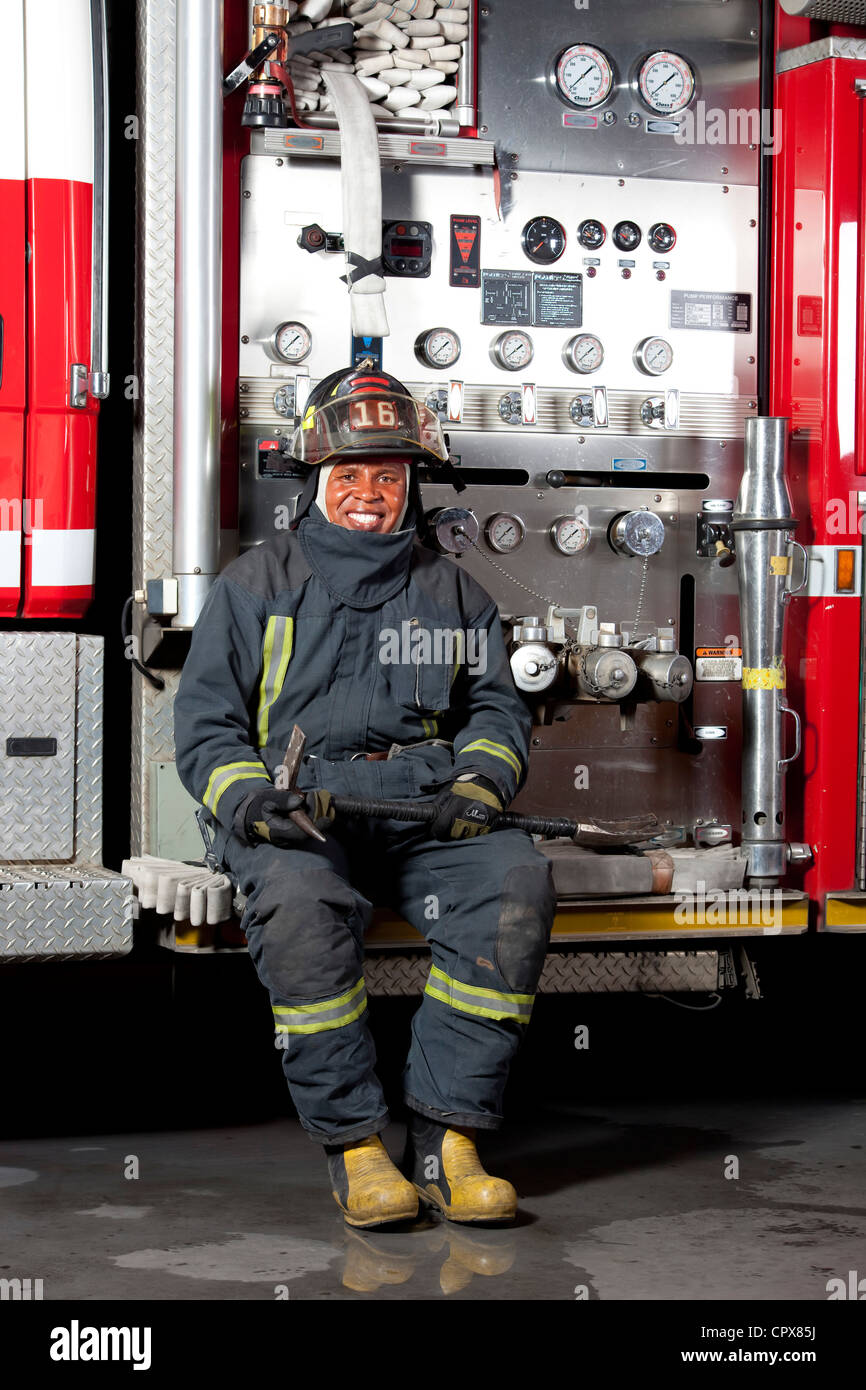 A fireman sitting on the fire engine, smiling Stock Photo - Alamy
