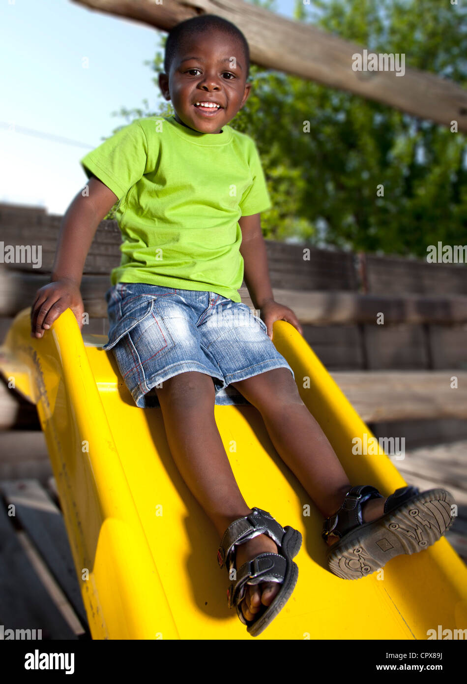 Child sitting on slide, smiling at camera Stock Photo - Alamy