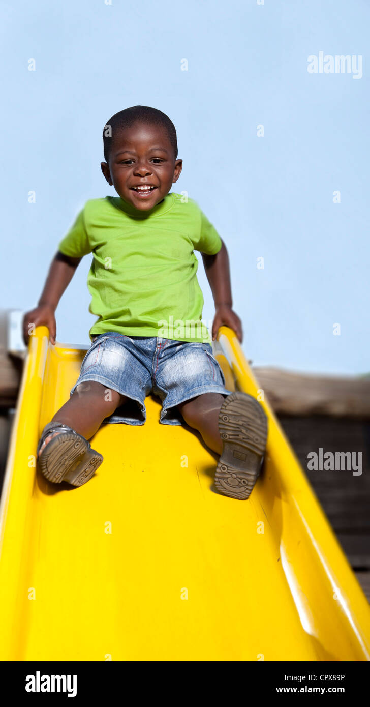 Child sitting on slide, smiling at camera Stock Photo - Alamy