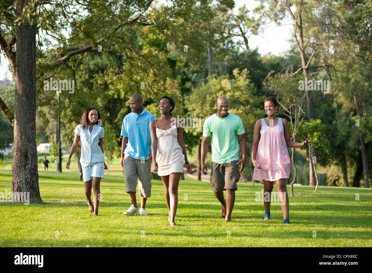 A group of young African friends walk together through a park Stock ...