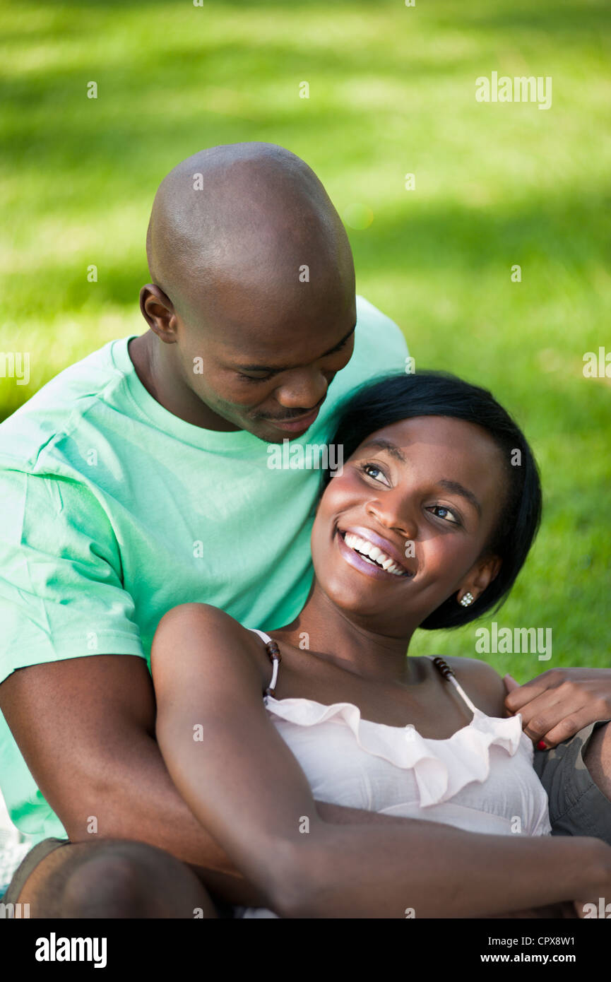 A young African couple sit together in a park Stock Photo - Alamy