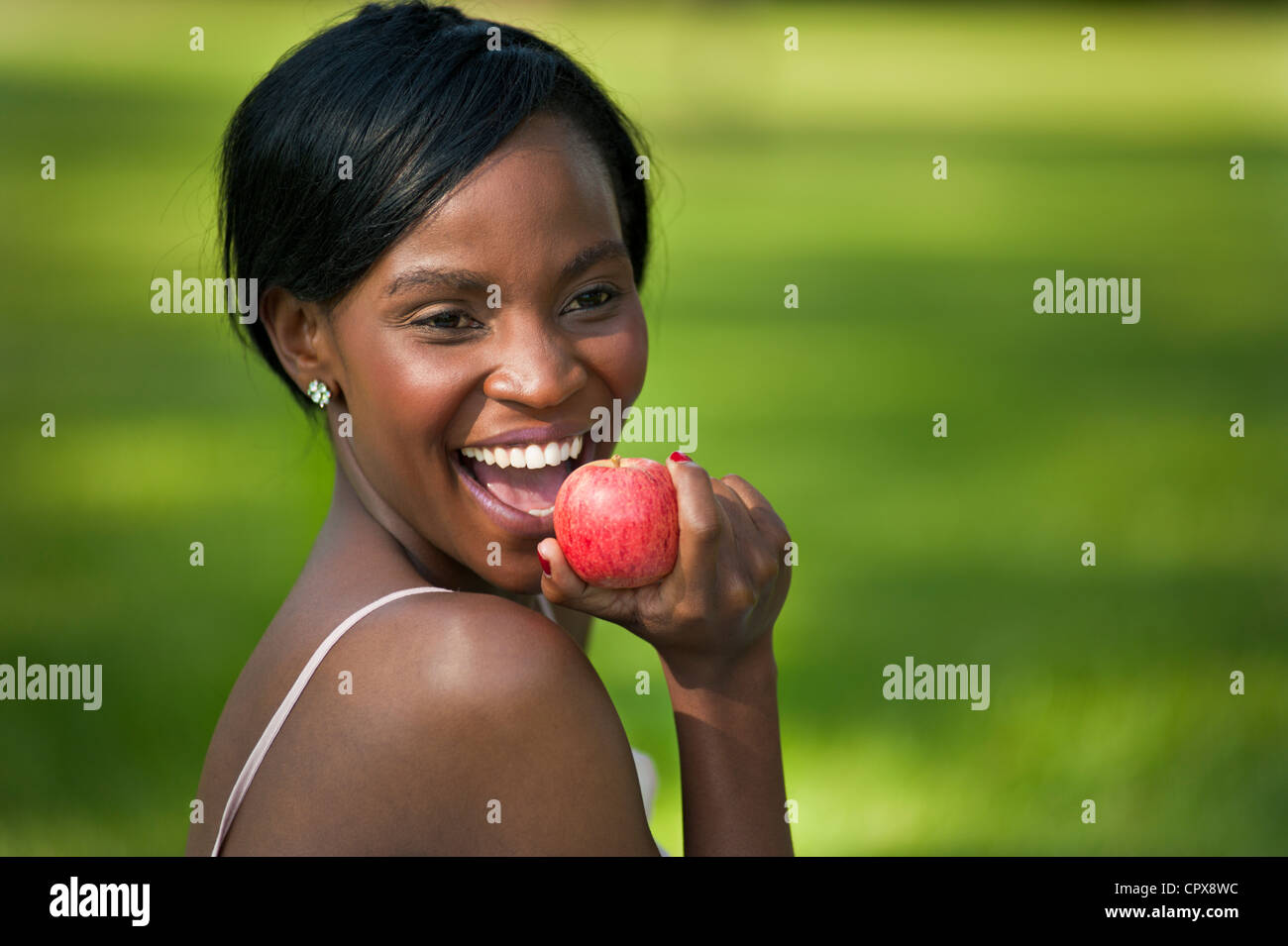 Young African female eating an apple in a park Stock Photo - Alamy
