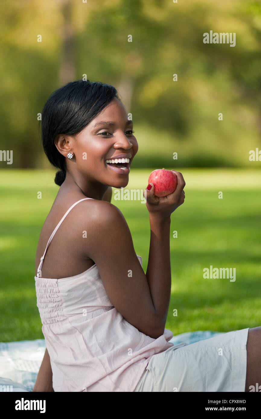 Young African female eating an apple in a park Stock Photo - Alamy