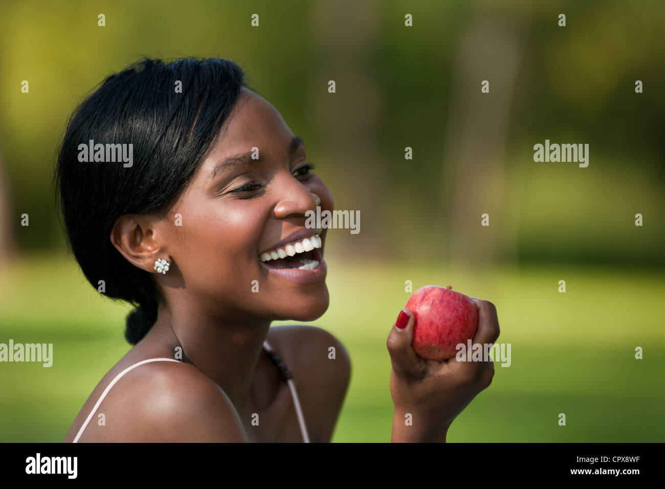 Young African female eating an apple in a park Stock Photo - Alamy