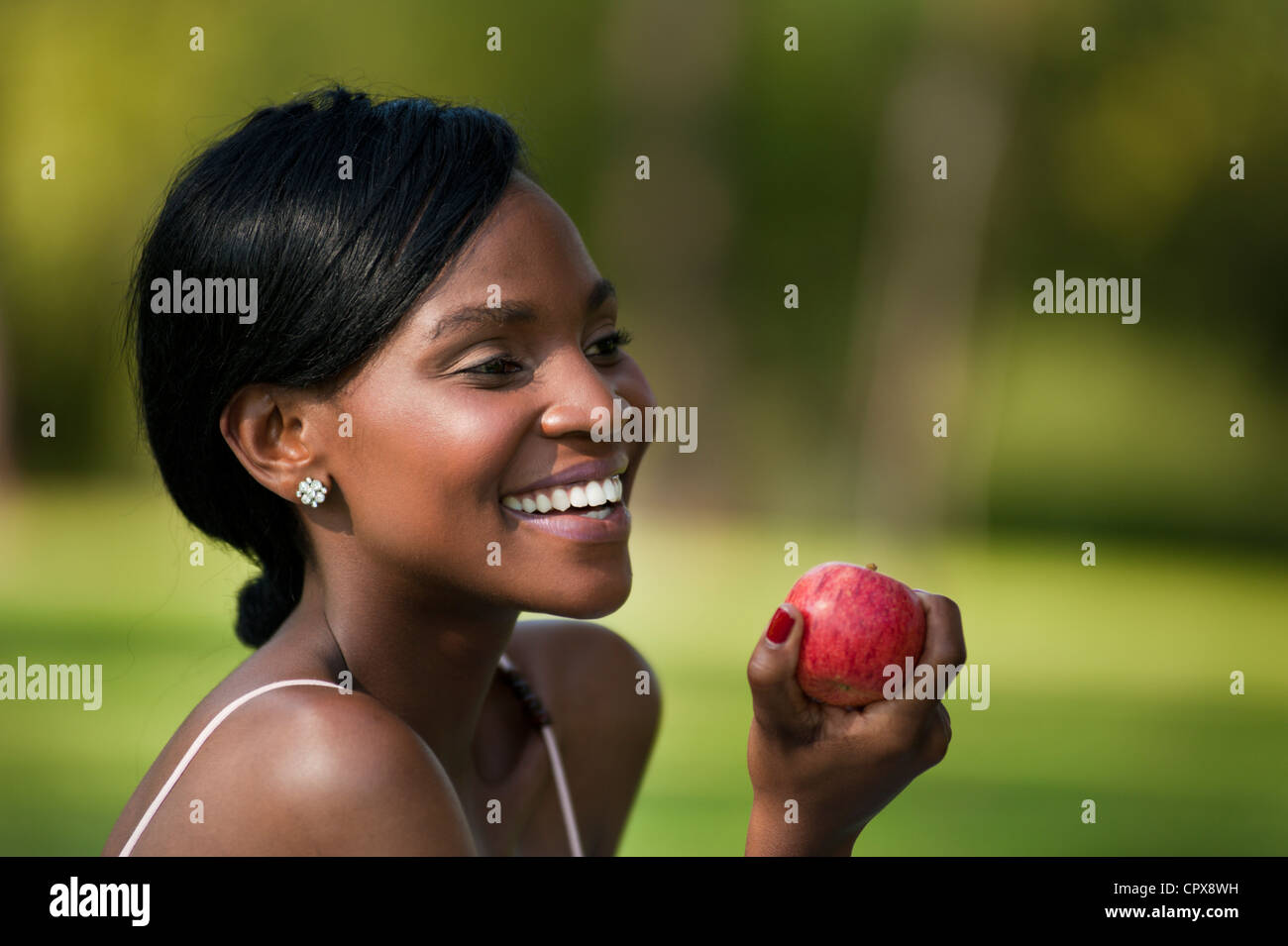 Young African female eating an apple in a park Stock Photo - Alamy