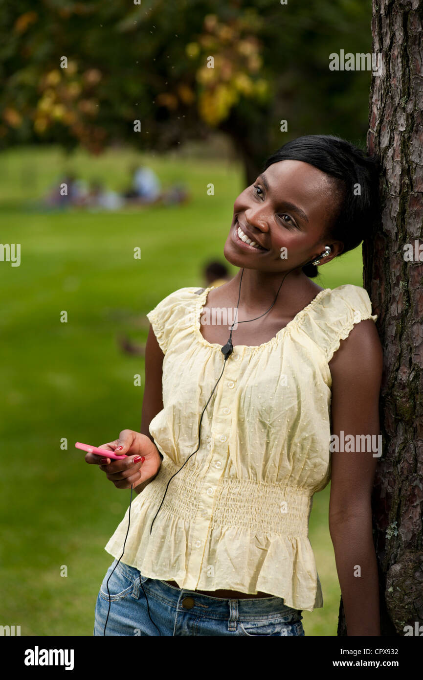 Young African Woman Standing Against A Tree In A Park Smiling Stock