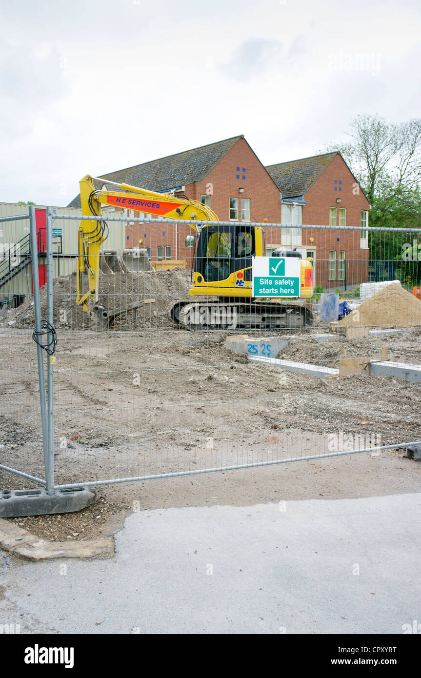 UK construction site with safety fencing, sign and mechanical digger ...