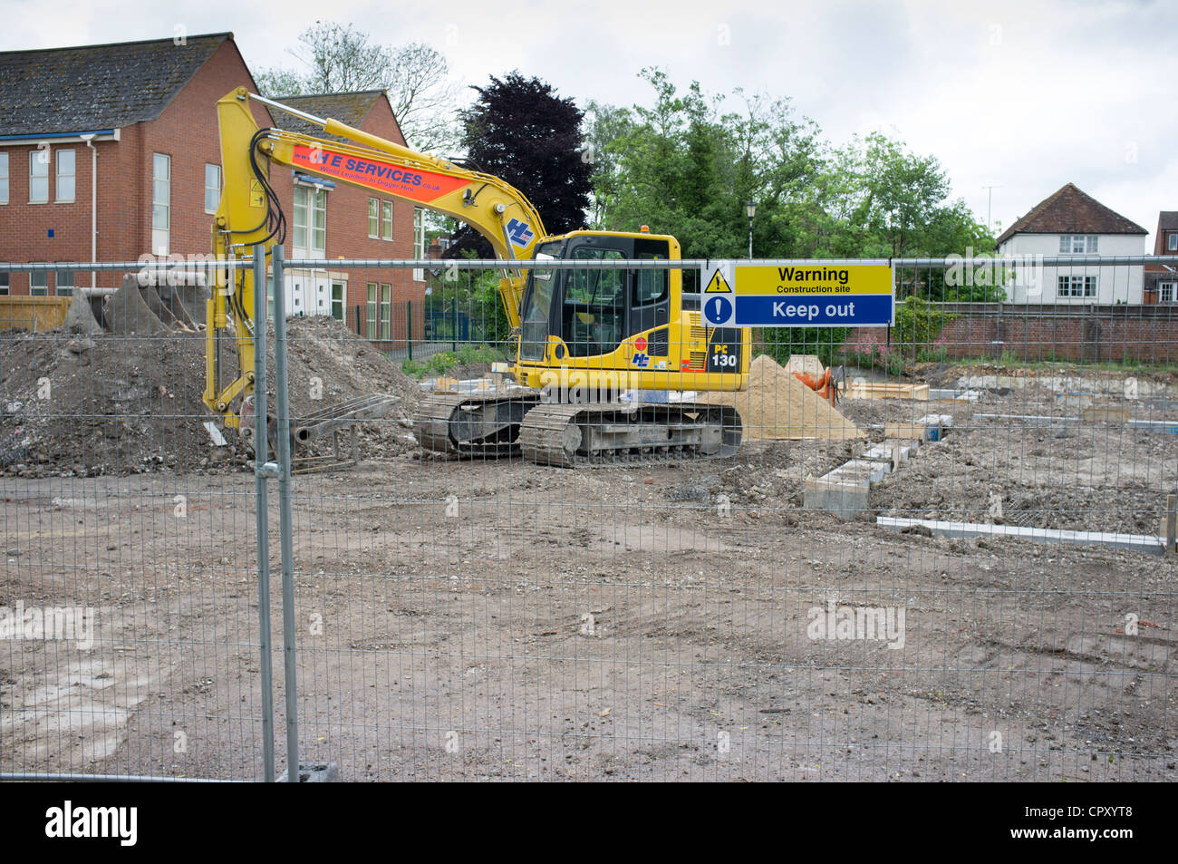 UK construction site with safety fencing, sign and mechanical digger ...