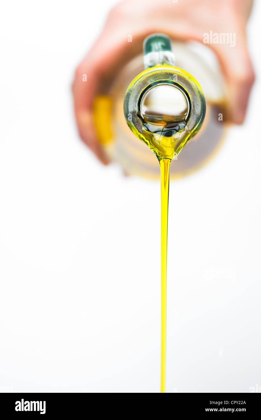Hand Pouring Rapeseed oil from a clear bottle against a white ...