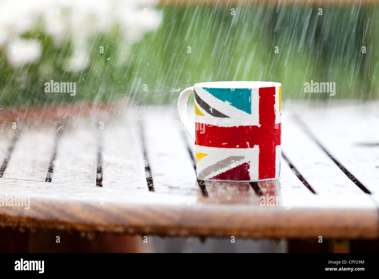 A Union Jack marked mug abandoned on an outside table in a rain storm ...